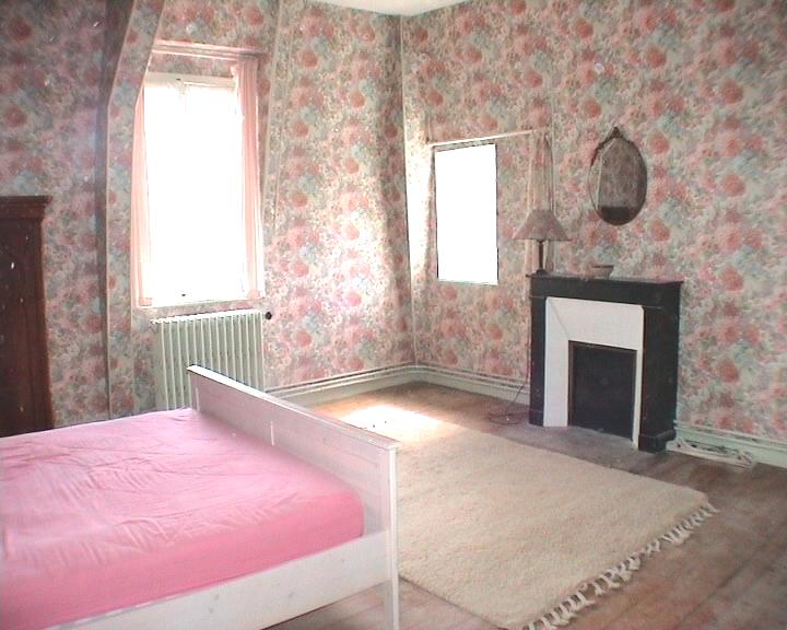 Een grote warm getinte roze kamer met dubbelbed.